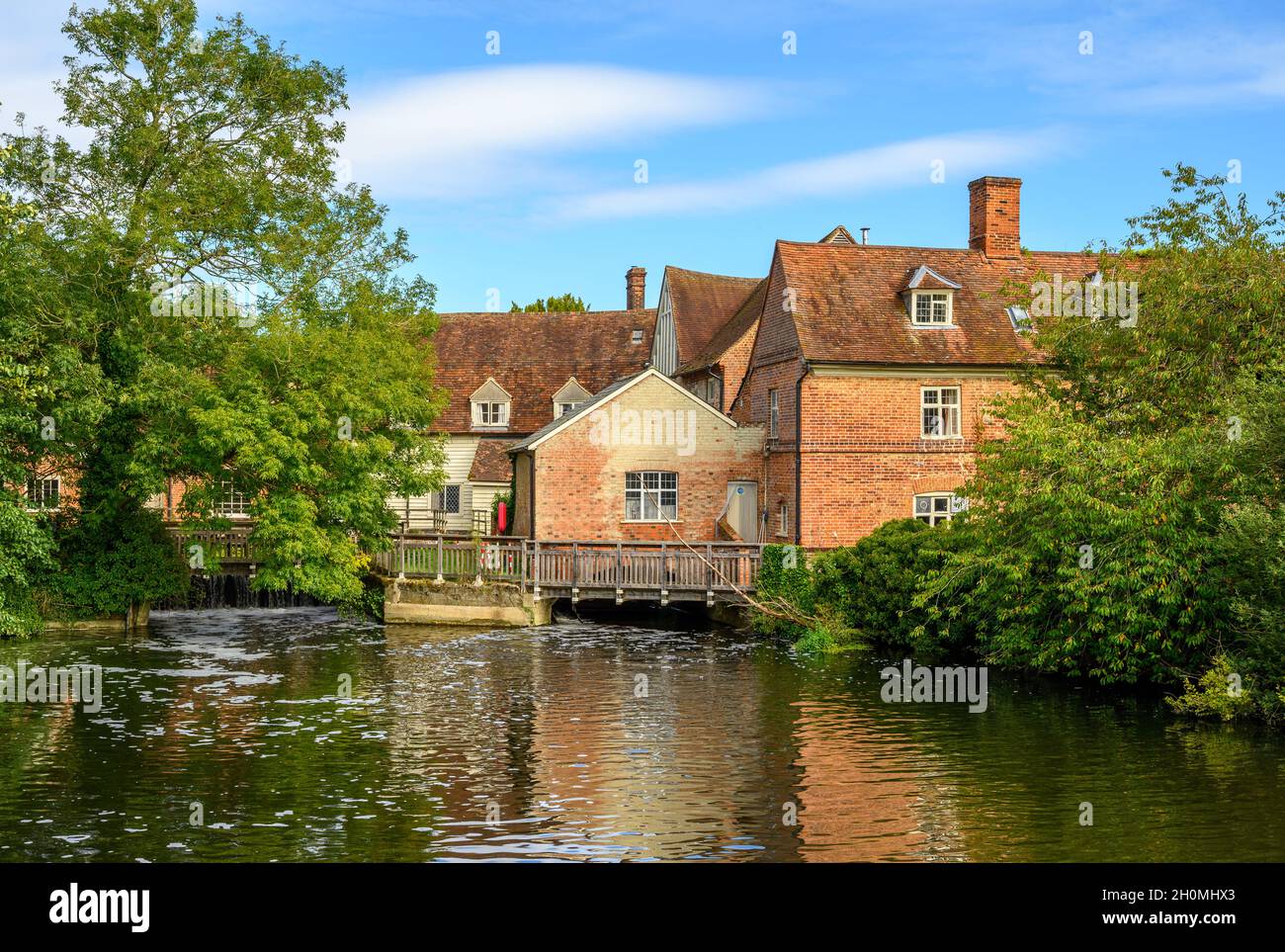 The red brick buildings of Flatford Mill viewed from across river Stour ...