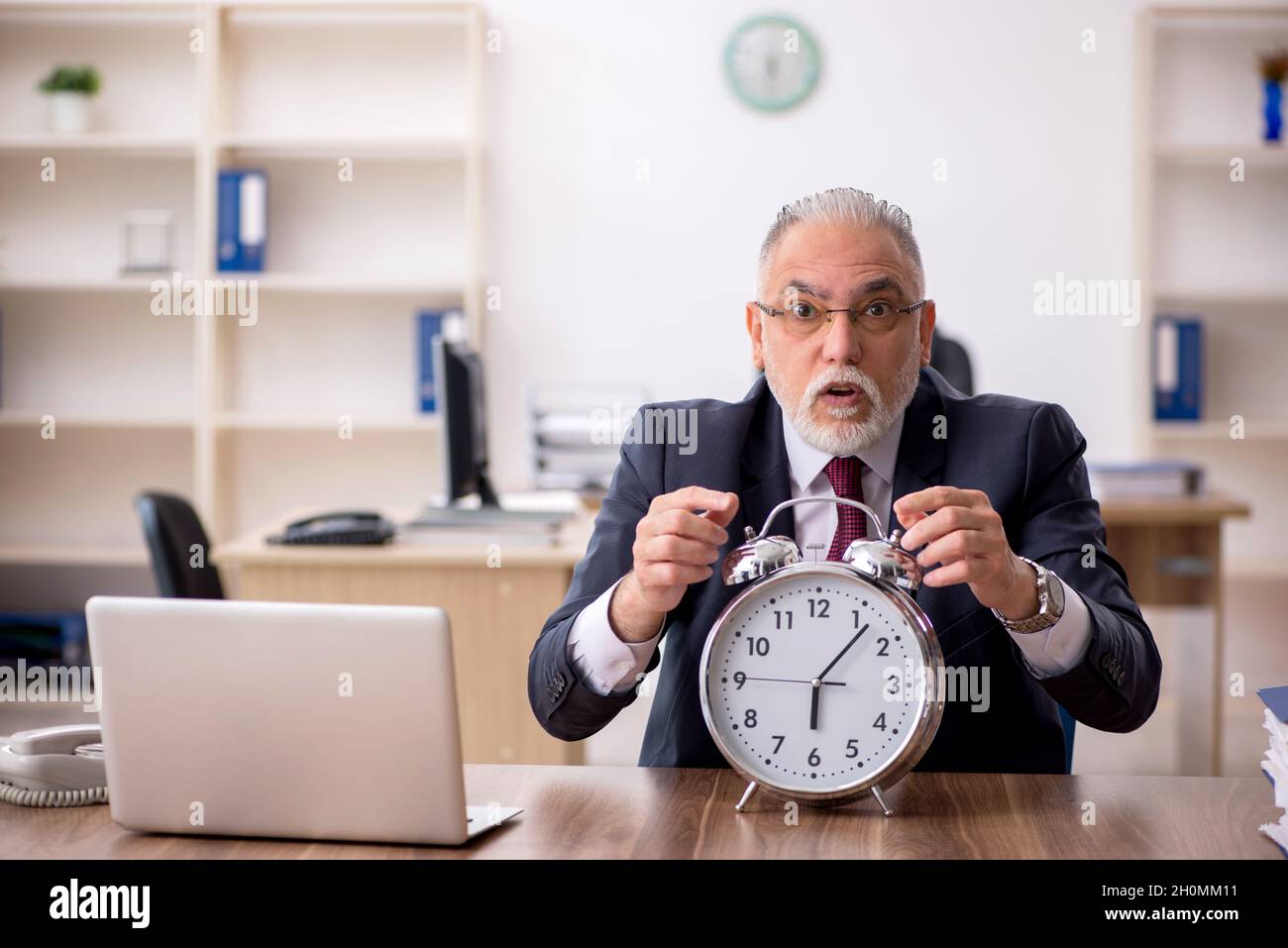 Old employee in time management concept Stock Photo - Alamy