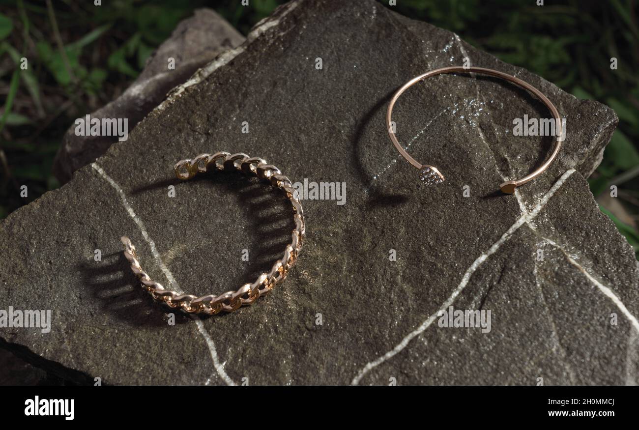 Top view of golden chain shape and heart shape bracelets on natural ...