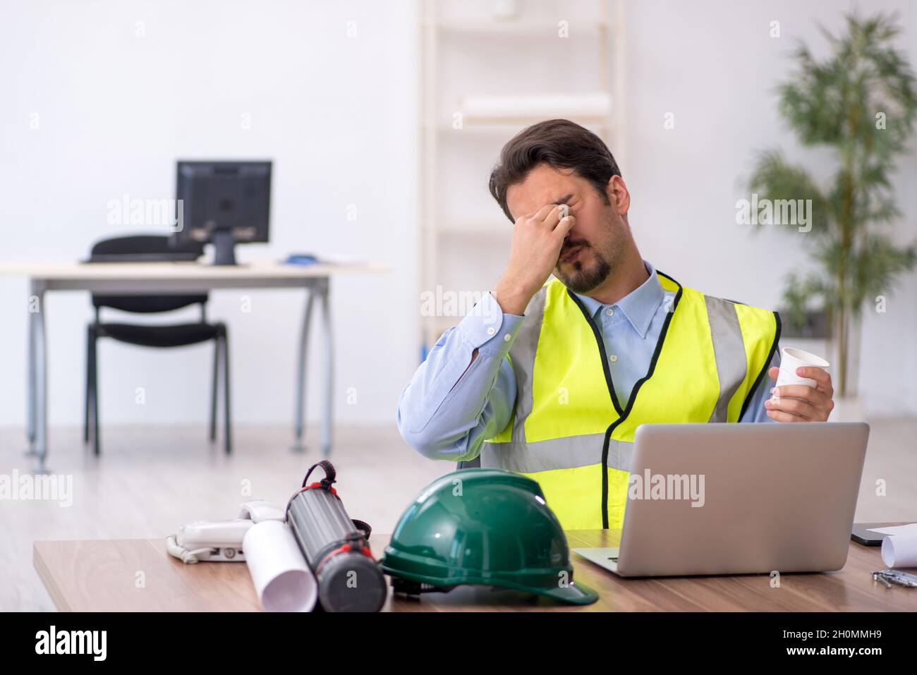 Tired young architect drinking coffee during break Stock Photo - Alamy
