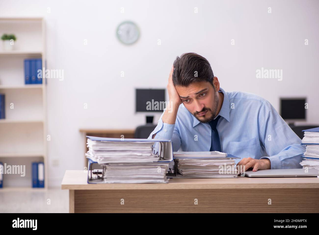 Young businessman employee and too much work at workplace Stock Photo ...