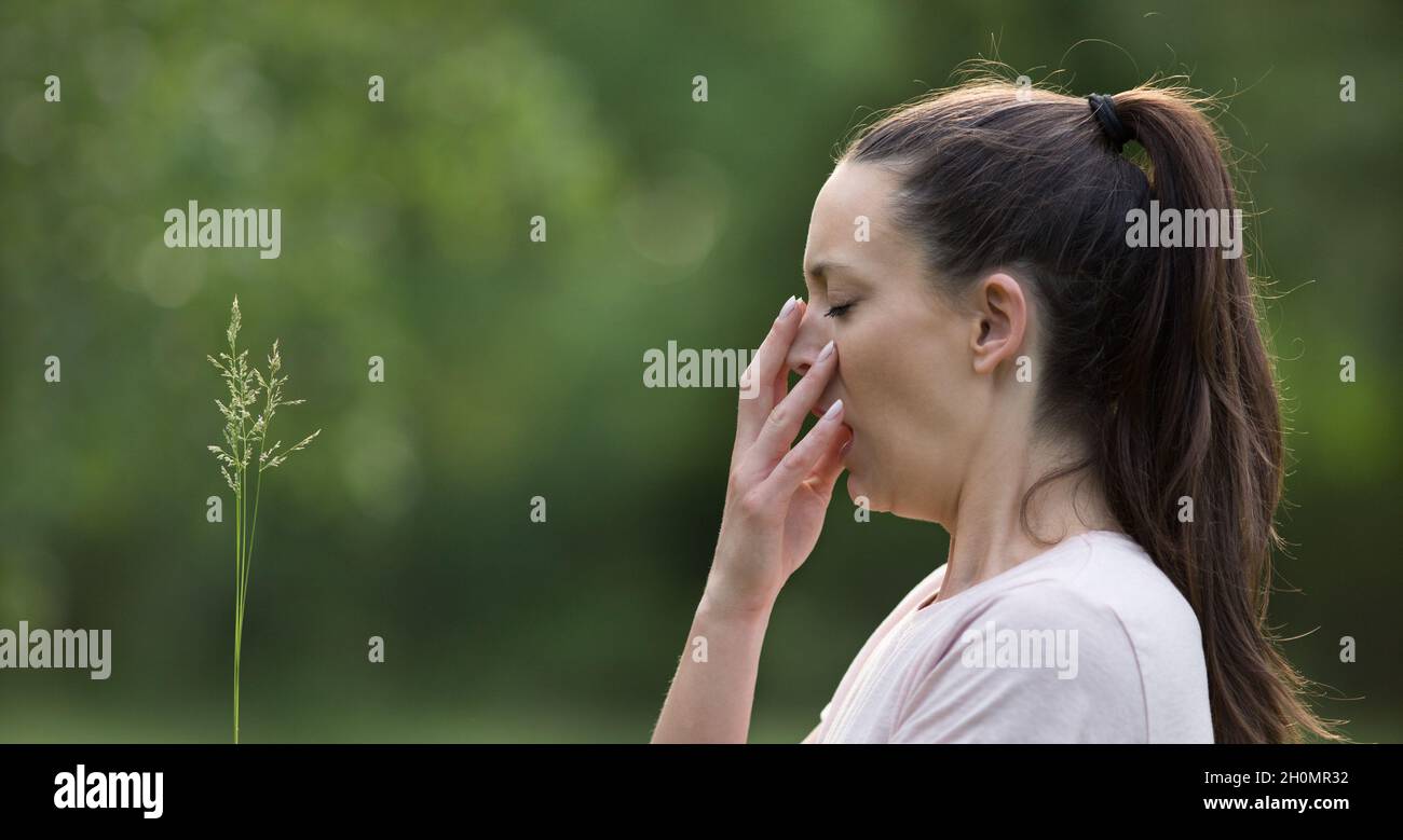 Portrait of pretty young woman sneezing in park with green background ...