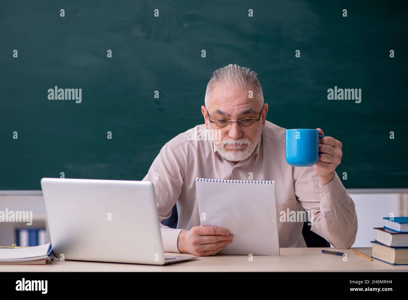 Old teacher drinking coffee in the classroom Stock Photo - Alamy