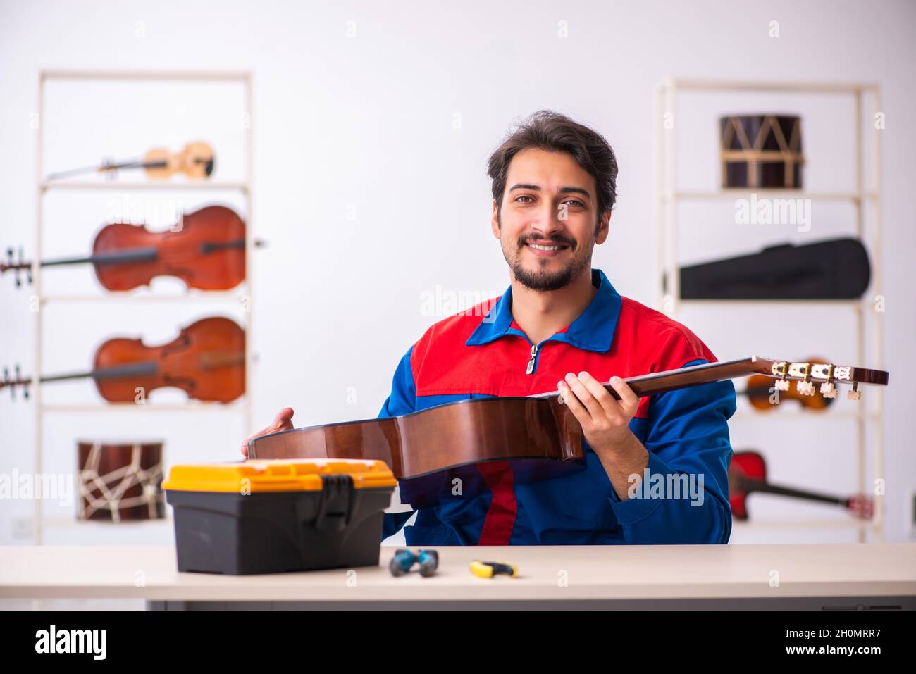 Young repairman repairing musical instruments at workplace Stock Photo ...