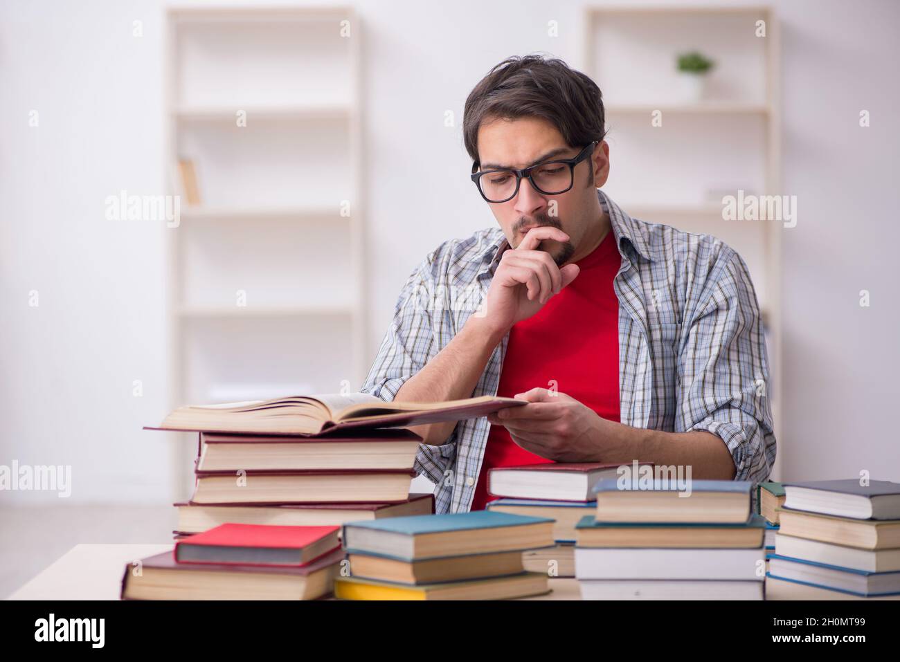 Young student and too many books in the classroom Stock Photo - Alamy