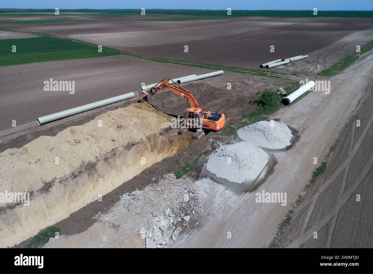 Aerial image of excavator digging pit for district heating line in ...