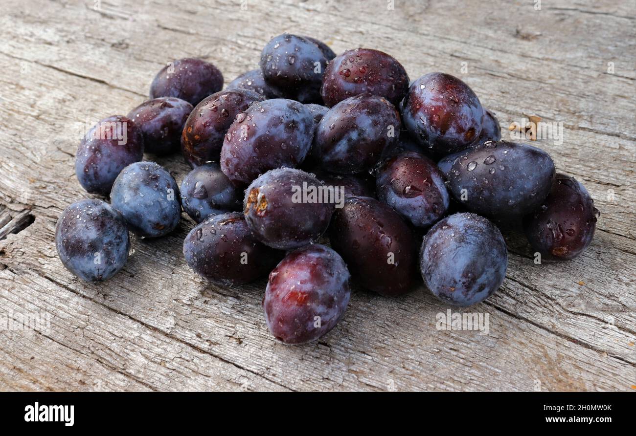 Fresh ripe plums on old rustic board Stock Photo - Alamy