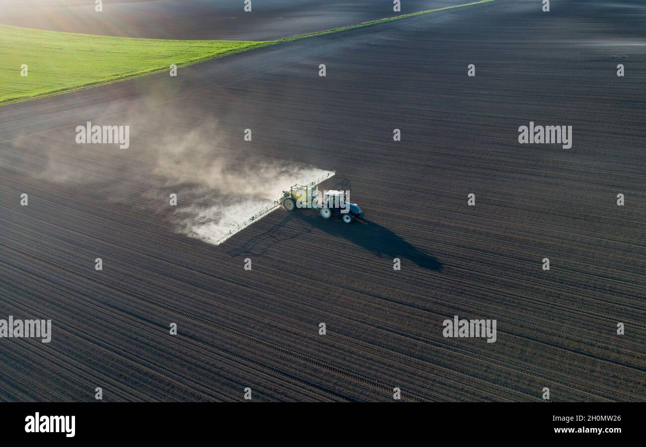 Aerial image of tractor spraying soil and young crop in springtime in ...