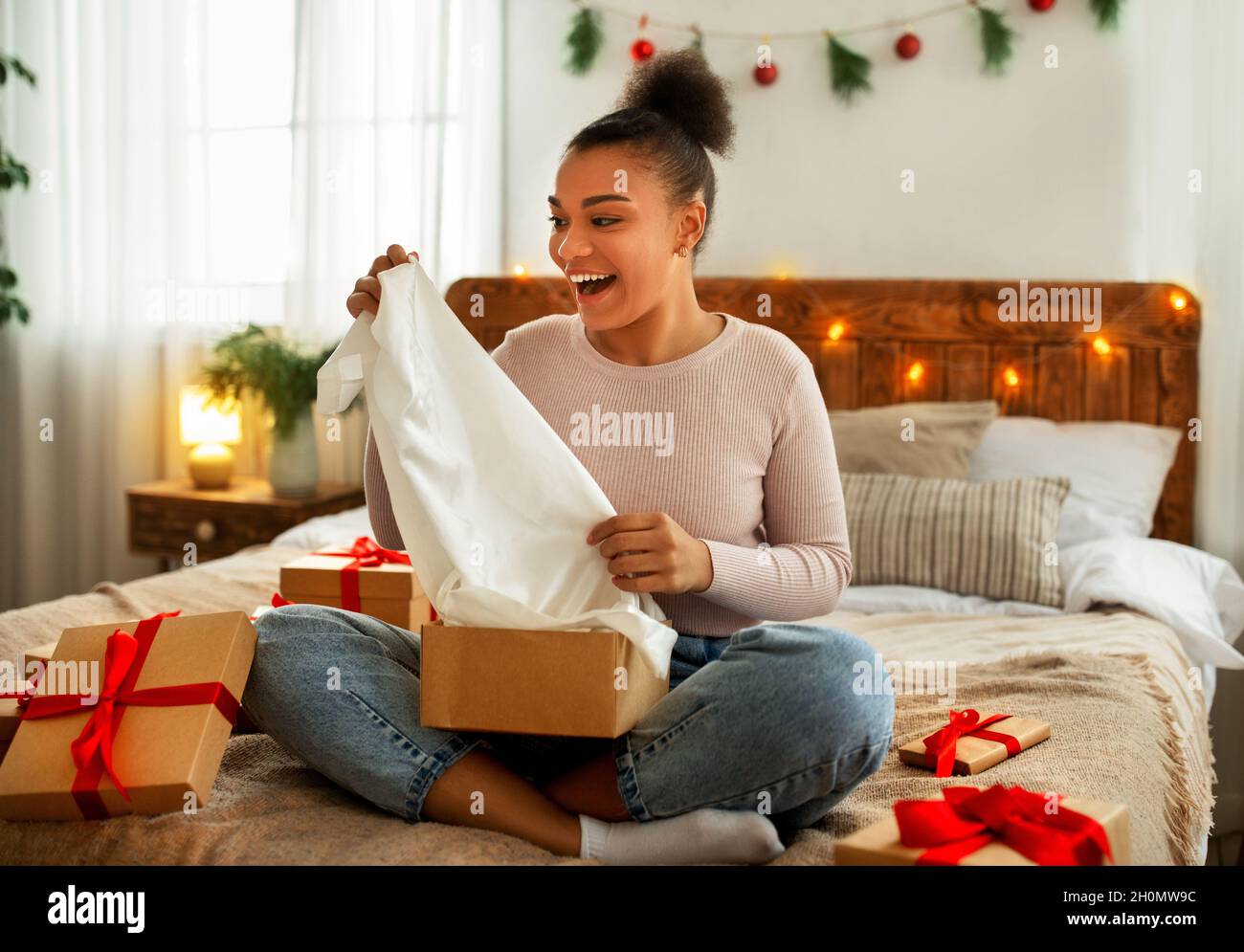 Overjoyed black lady opening Christmas gift box, holding new t-shirt ...