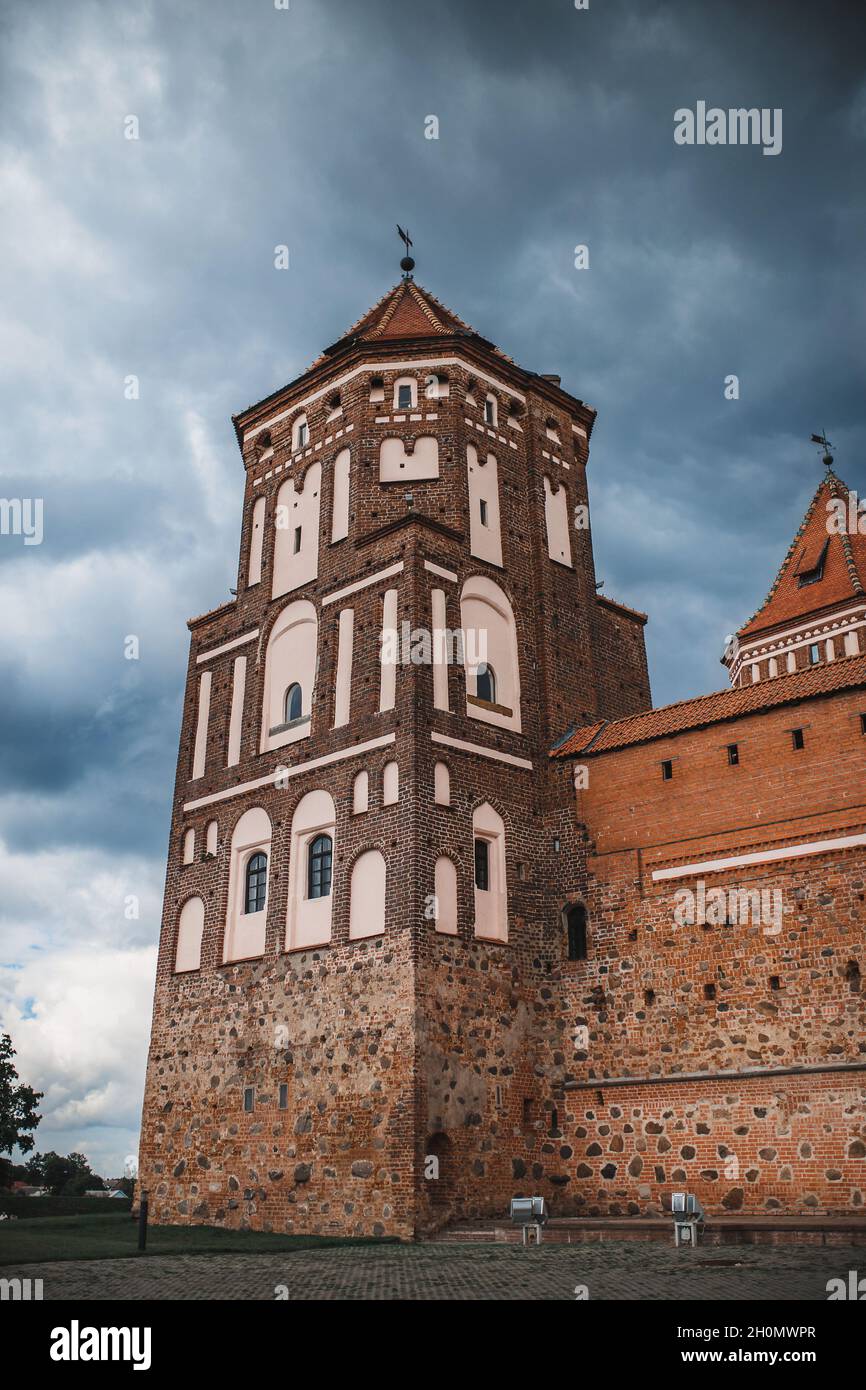 Mysterious medieval red brick castle with tiled roof in cloudy weather ...