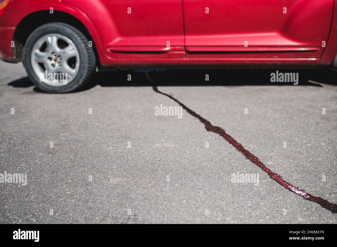 A stream of liquid on the pavement from under the car - oil flows from ...