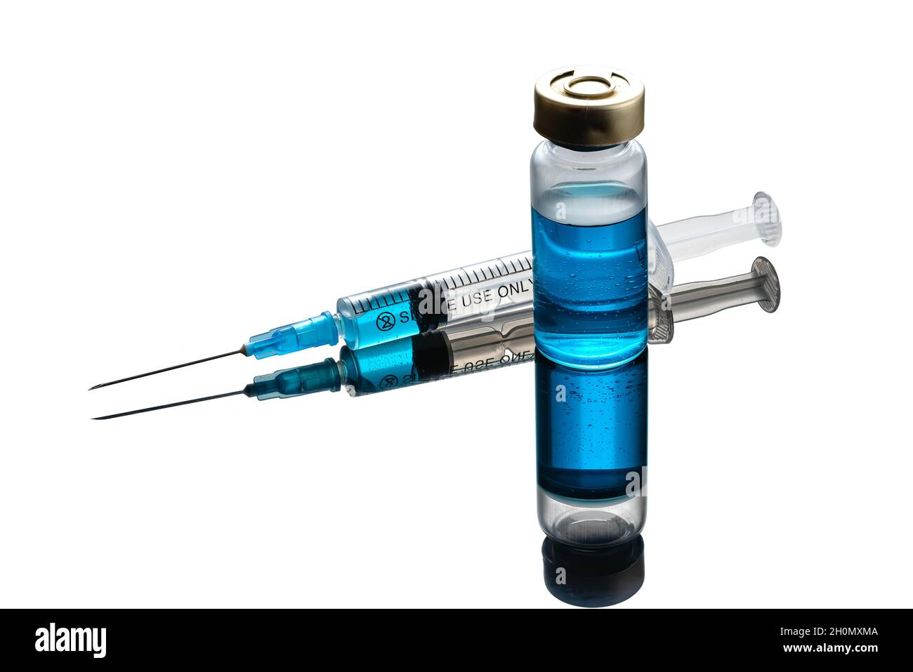 Injection syringe and a bottle of blue liquid, with a reflection in the ...