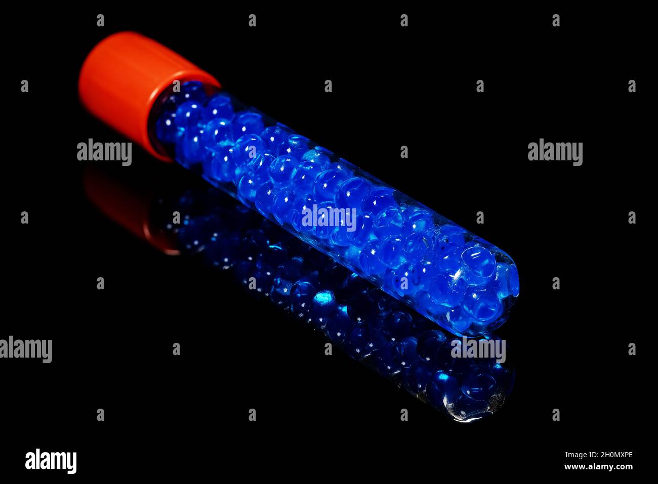 Blue gel balls in a medical vial isolated on black background. The ...