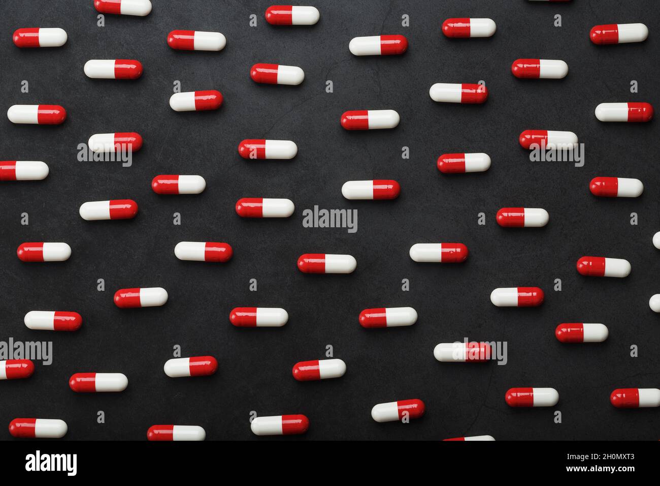 A pattern of red and white pills of medical pills on a black background ...