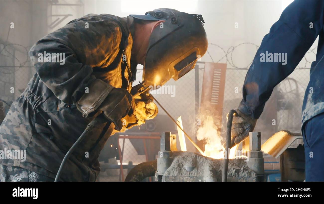 Worker is engaged in welding. His partner helps him Stock Photo - Alamy