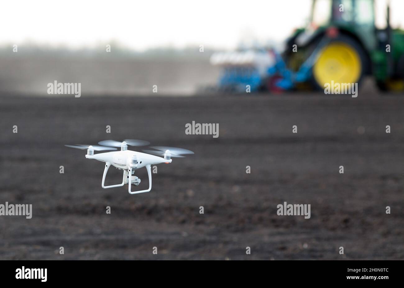 Close up of drone flying above farmland with tractor working in ...