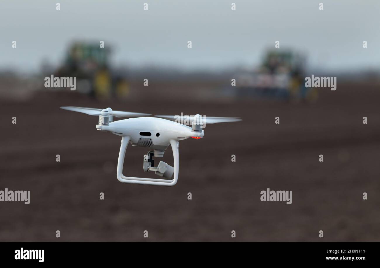 Close up of drone flying above farmland with tractors working in ...