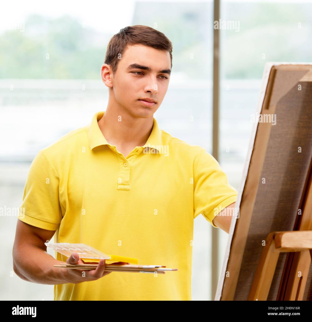 The young male artist drawing pictures in bright studio Stock Photo - Alamy