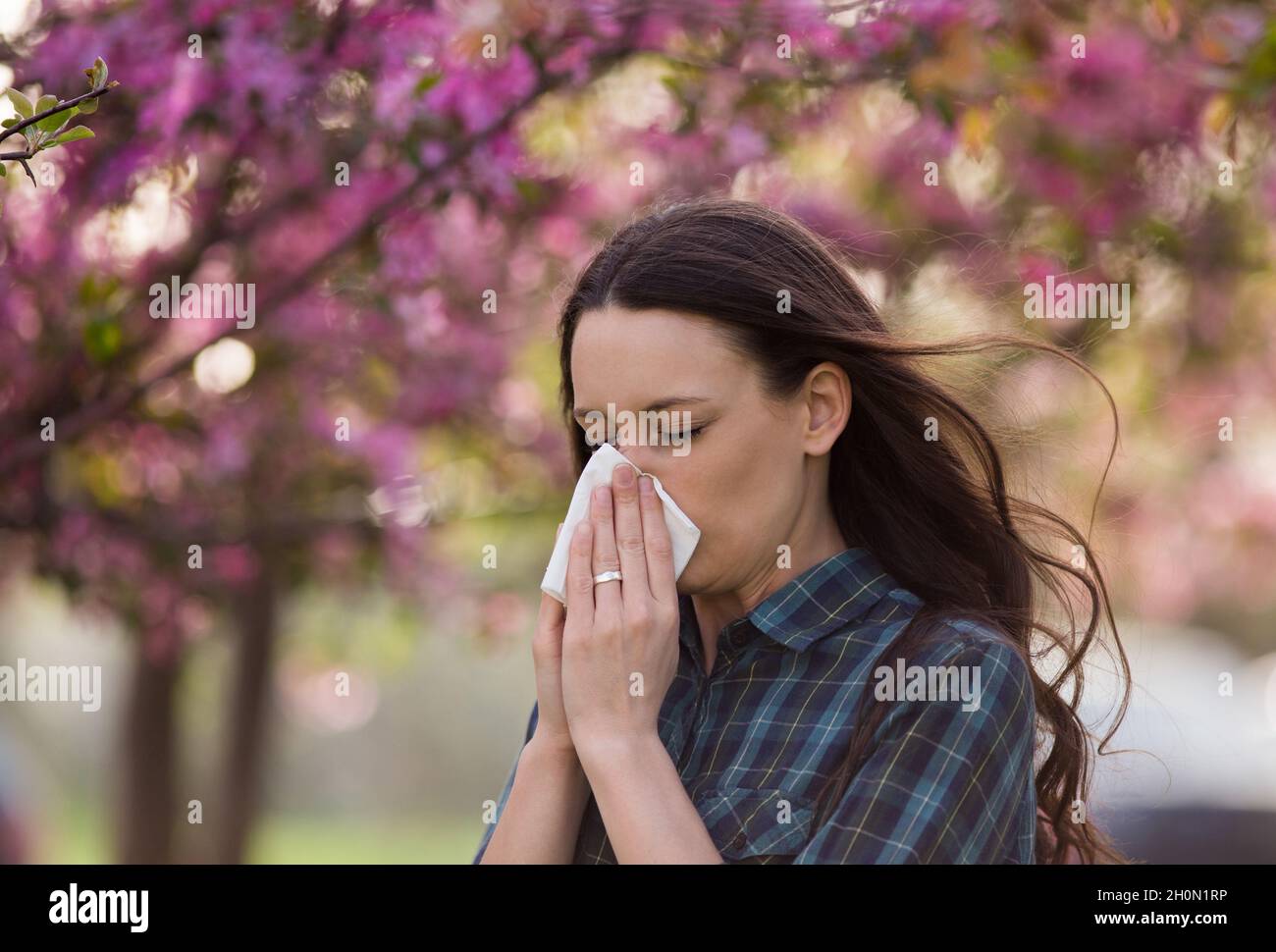 Young pretty girl blowing nose in front of blooming tree. Spring allergy concept Stock Photo - Alamy