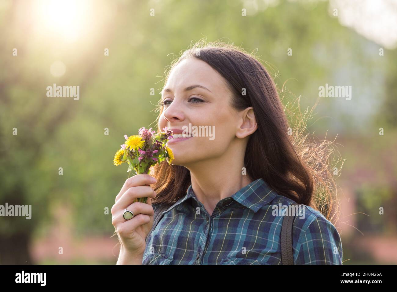 Pretty young woman smelling field flowers in park. Peaceful and special ...