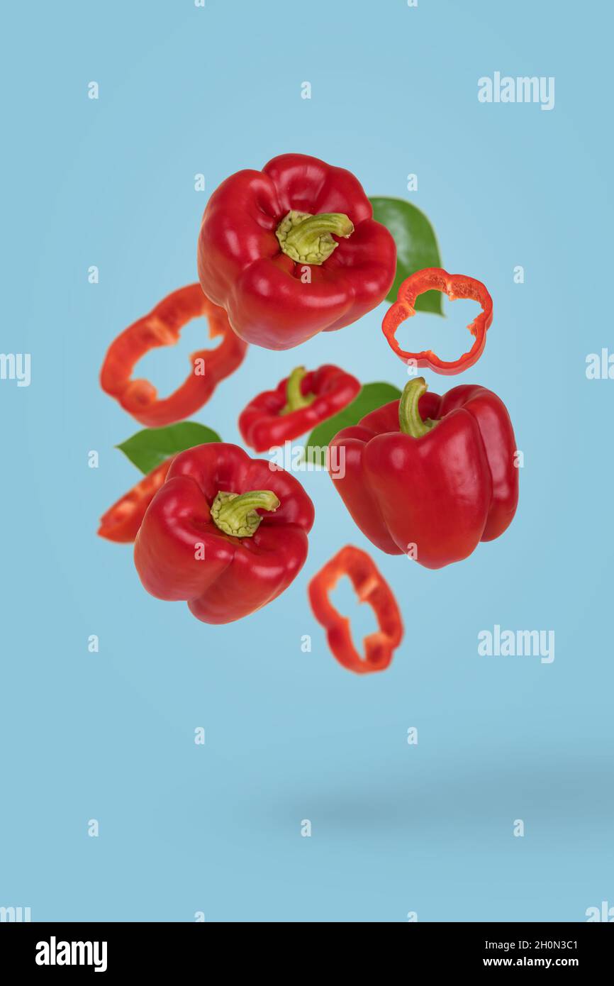 Creative idea with fresh ripe whole and sliced red bell peppers flying ...