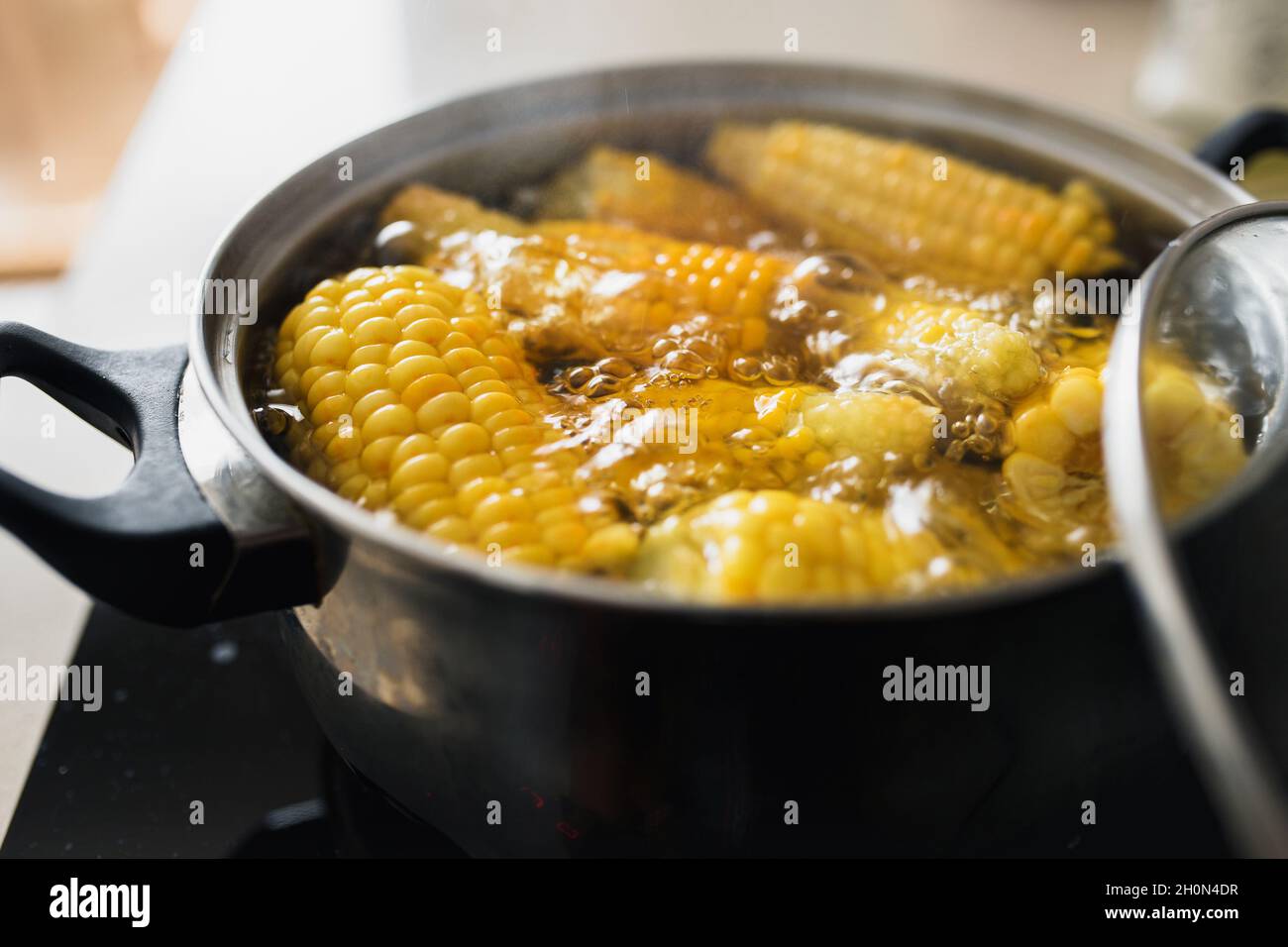 Close-up of corn in boiling water on the background of the kitchen ...