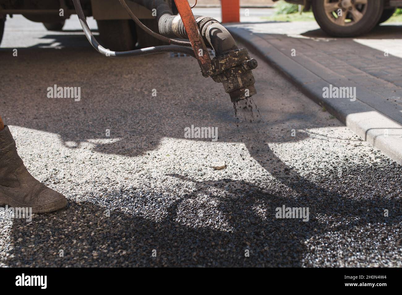 Road works using hot bitumen emulsion and crushed stone during asphalt ...