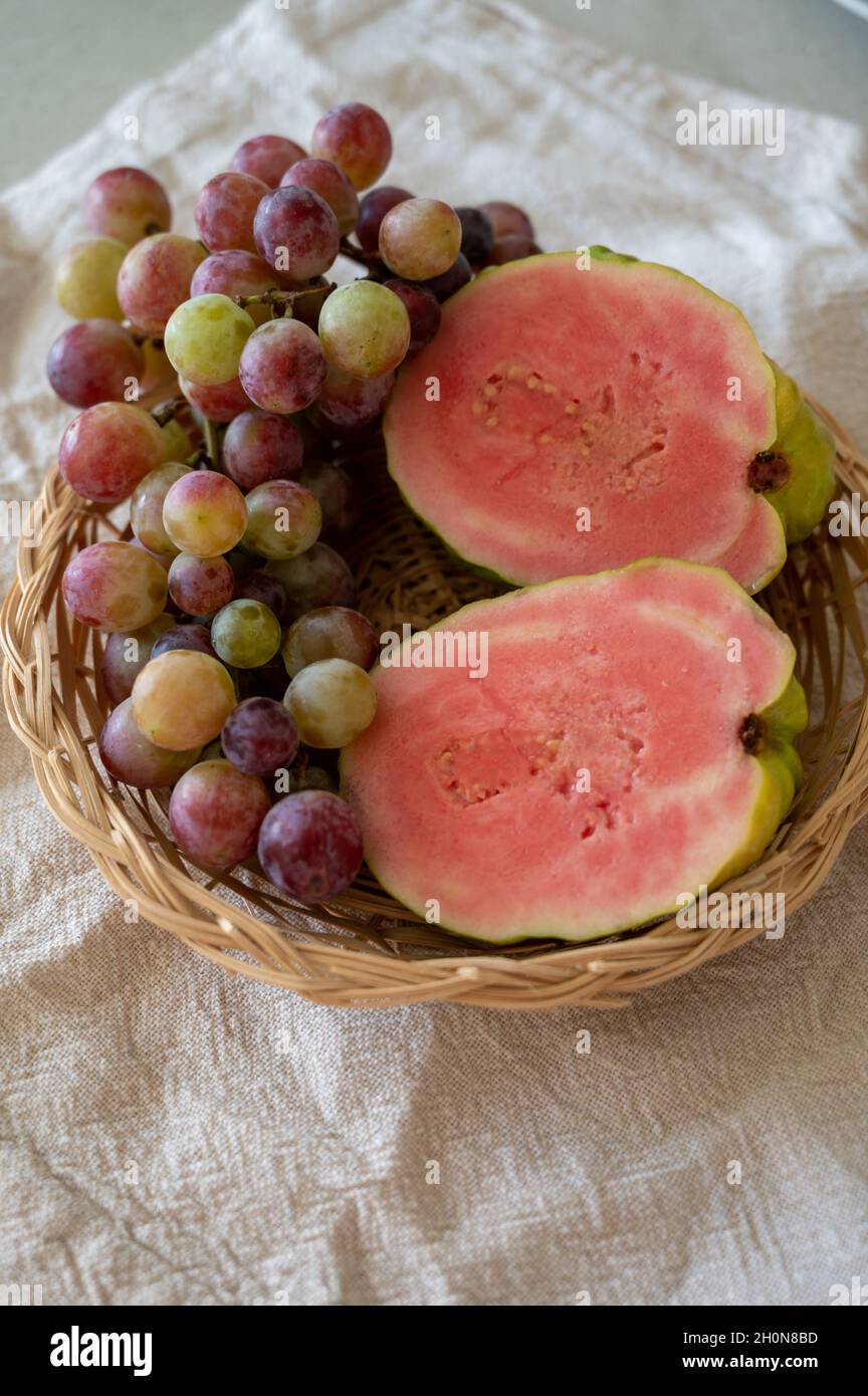 Fresh ripe aromatic pink guava tropical fruit and sweet table grapes ...