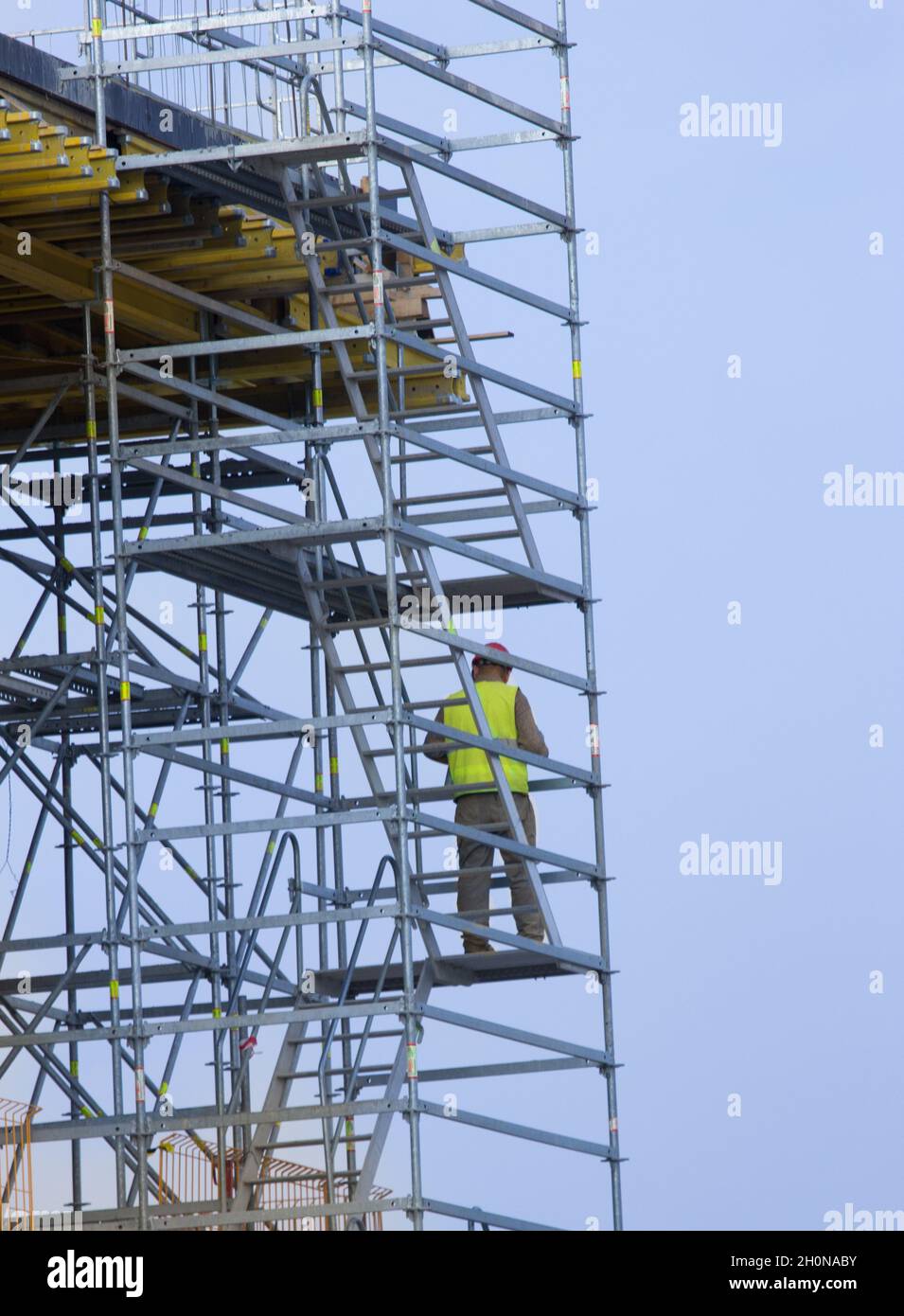 Construction worker walking on scaffolding steel stairs at building ...
