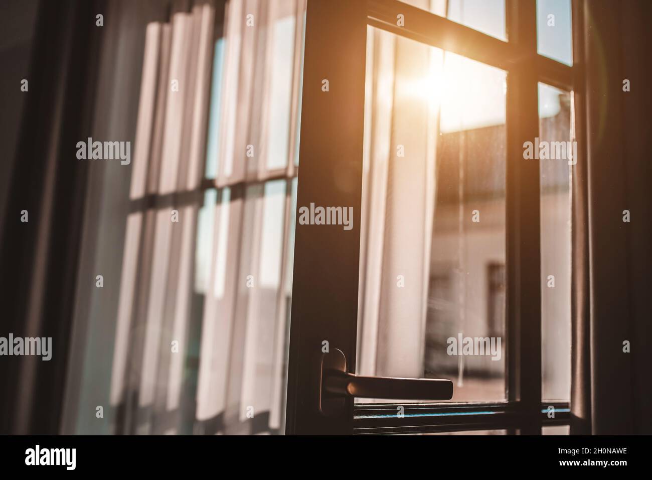 Bright flare of the setting sun through the curtains in an open window ...