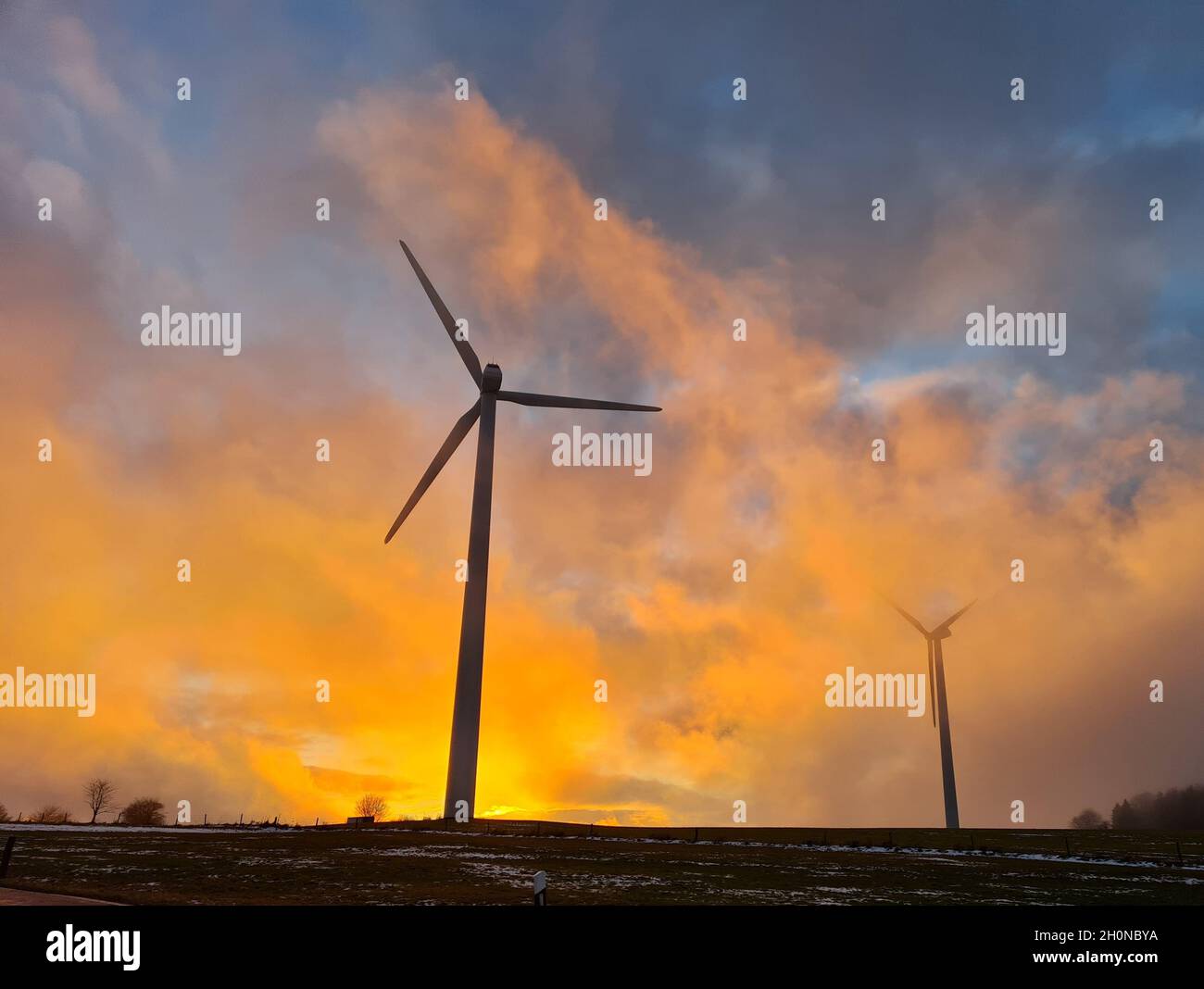Beautiful scene of wind energy turbines under an orange sky at sunset ...