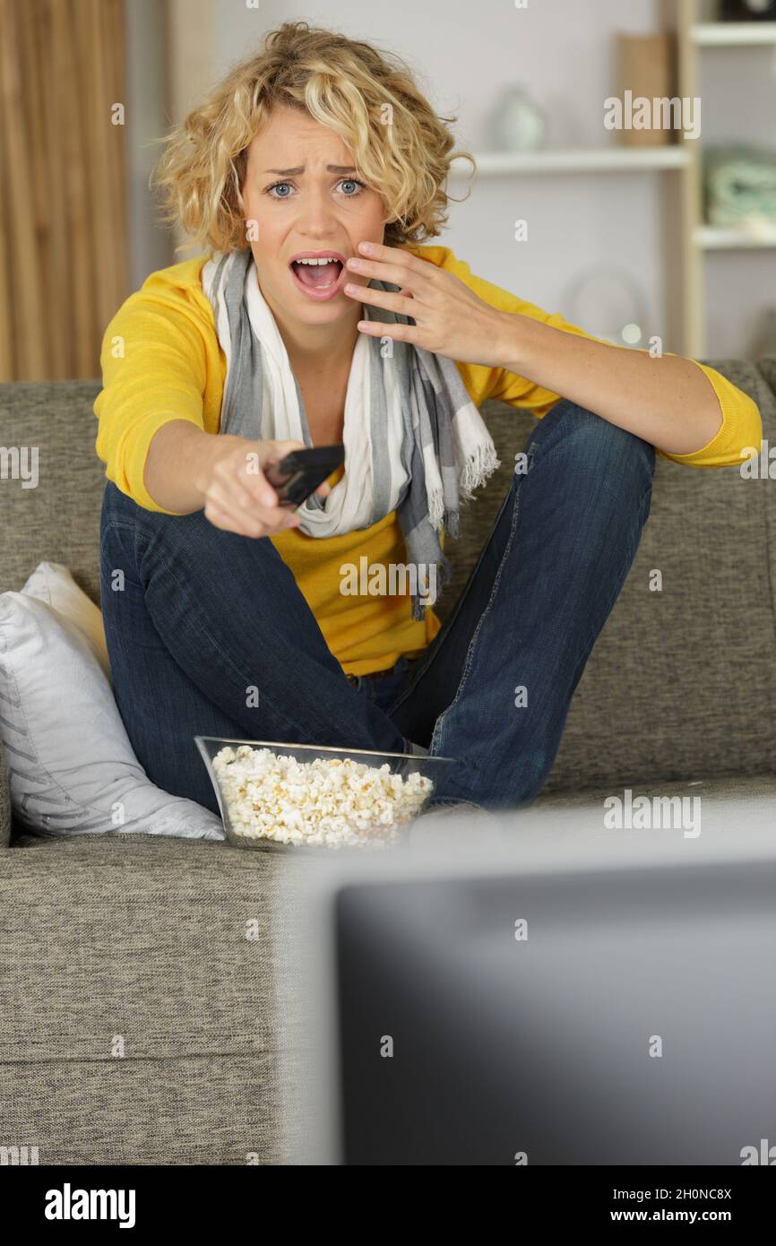 sad upset woman using remote controller having bucket with popcorn ...