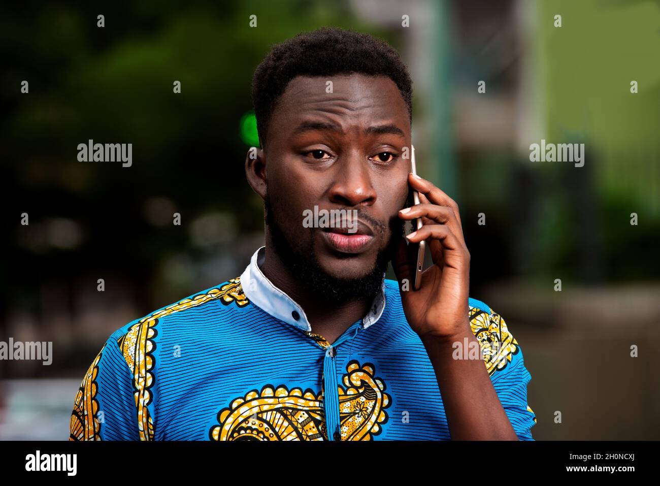 young man in traditional dress standing outdoors communicating with ...
