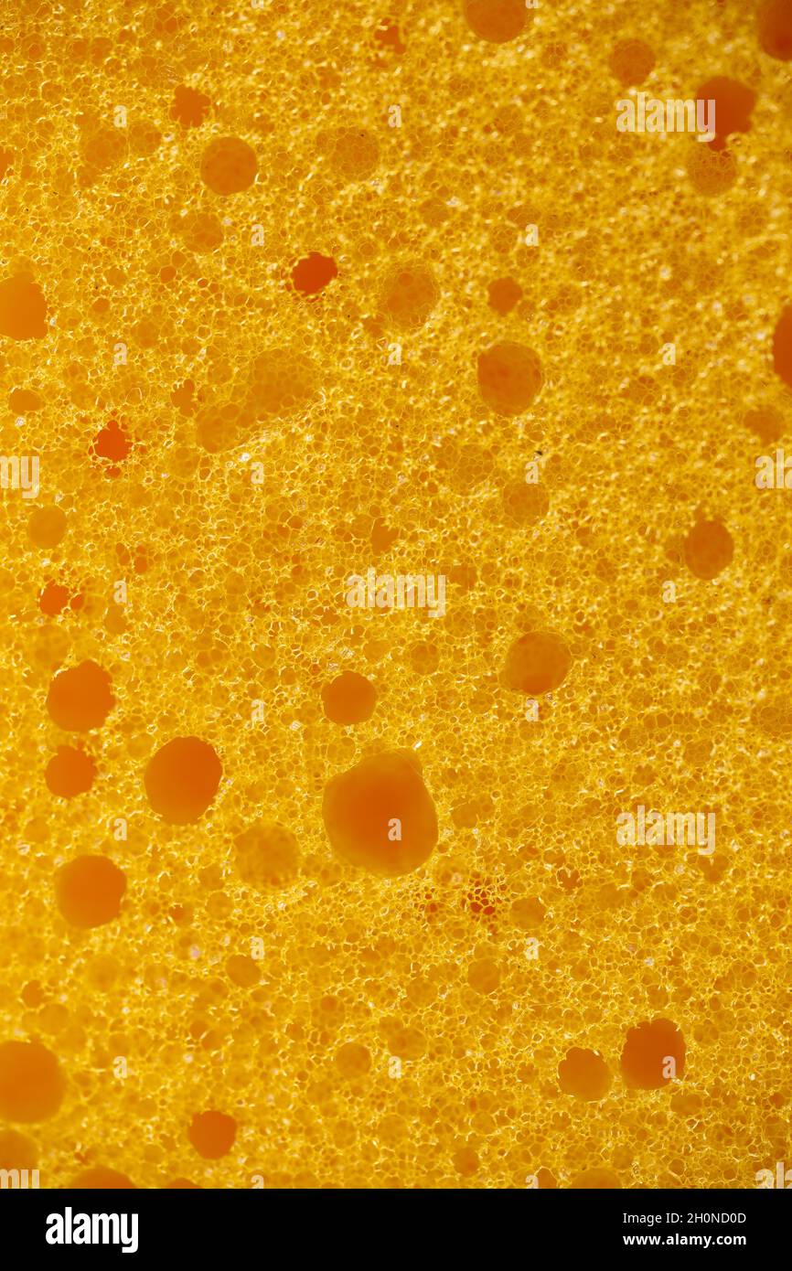Yellow foam rubber texture, synthetic sponge with pores, close-up ...