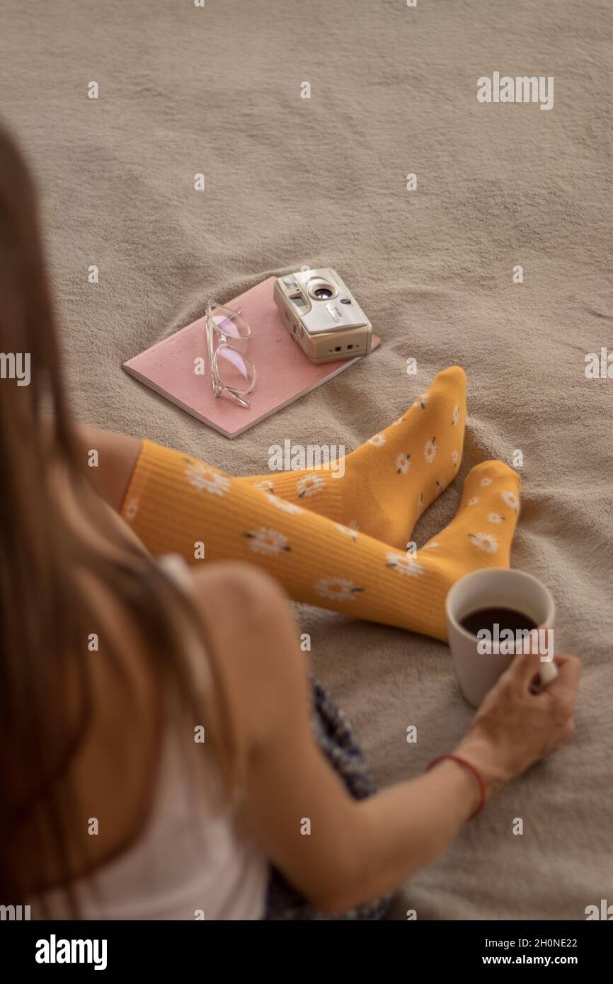 Vertical back view of a female in warm yellow socks drinking coffee ...