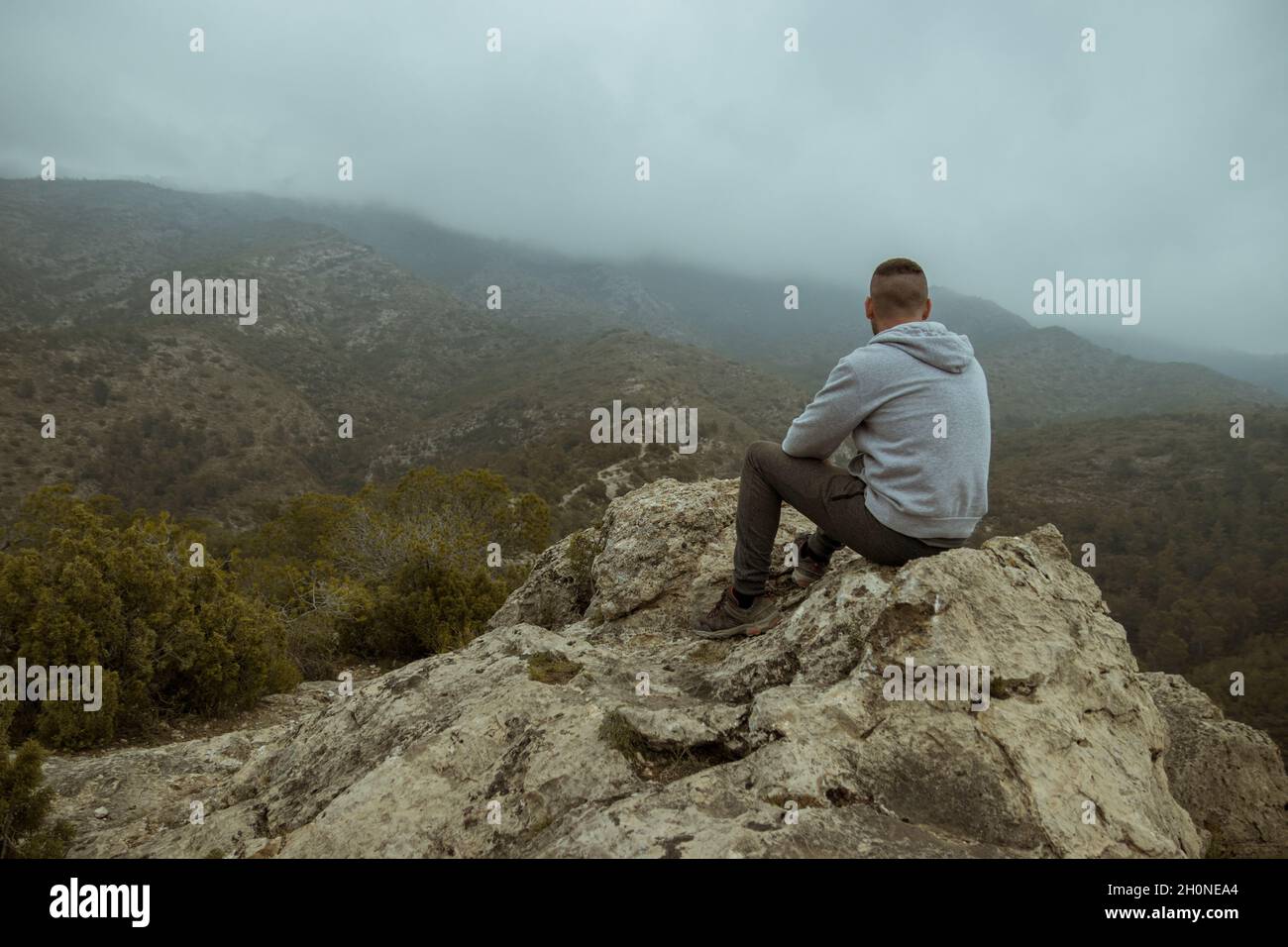Male sitting on a rock looking back hi-res stock photography and images ...