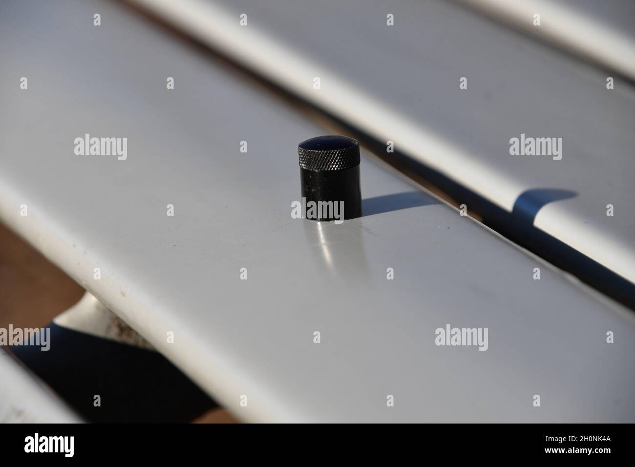 Black micro geocache. container sits on a silver bench Stock Photo - Alamy