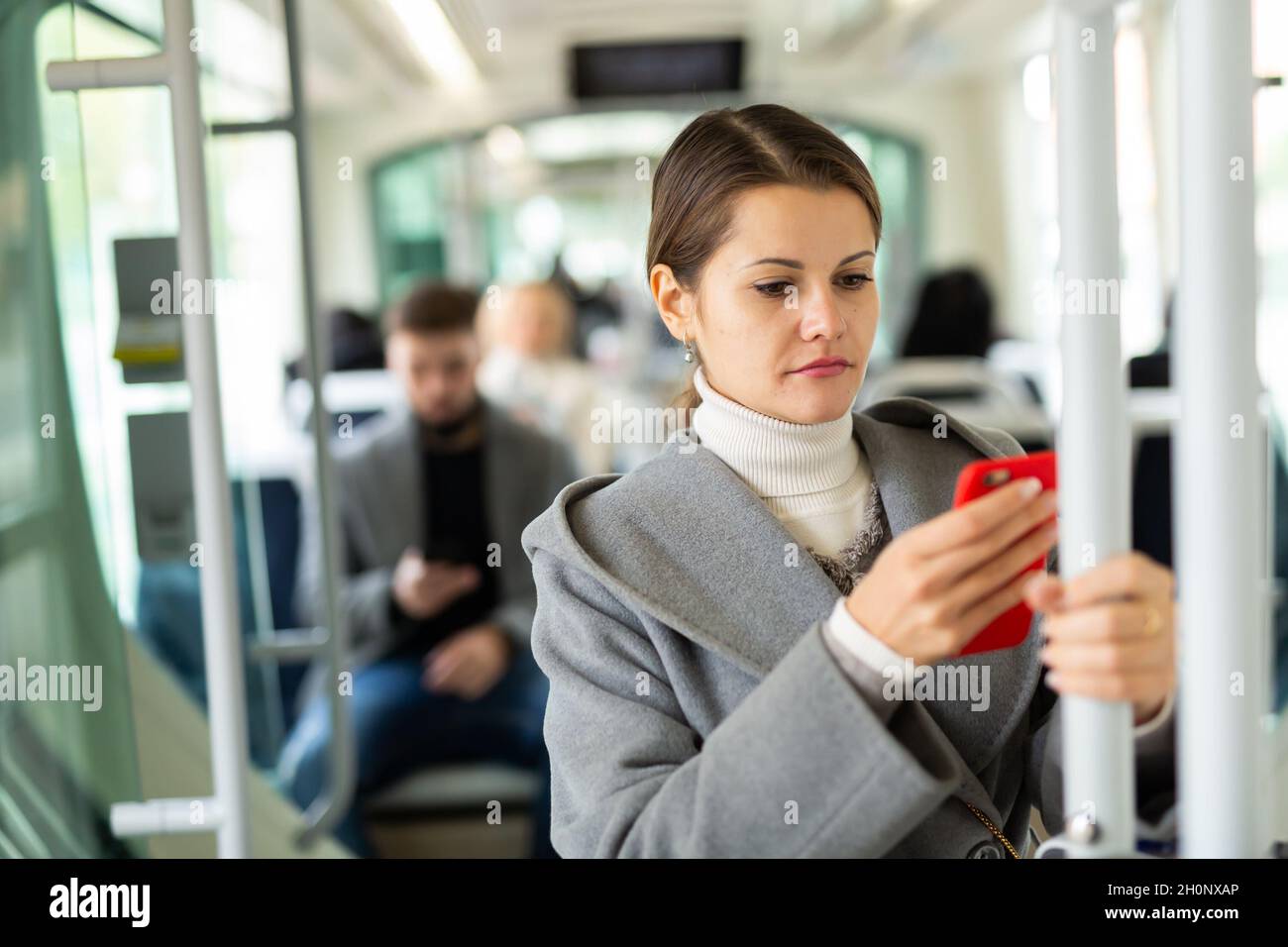 Positive woman reading from mobile phone screen in tram Stock Photo - Alamy