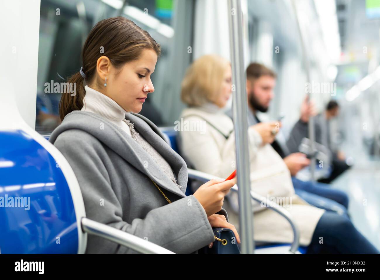 Positive woman reading from mobile phone screen in metro Stock Photo ...