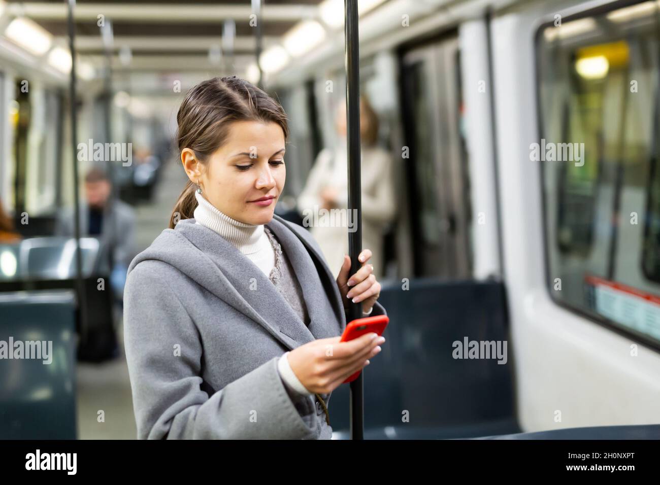 Positive woman reading from mobile phone screen in tram Stock Photo - Alamy