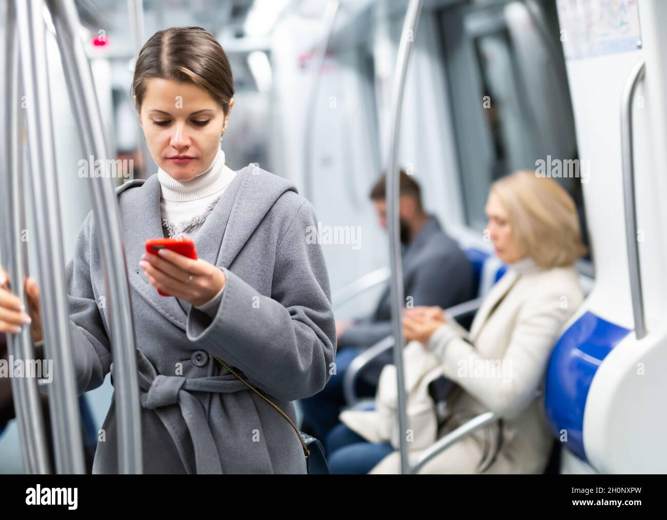 Positive woman reading from mobile phone screen in metro Stock Photo ...