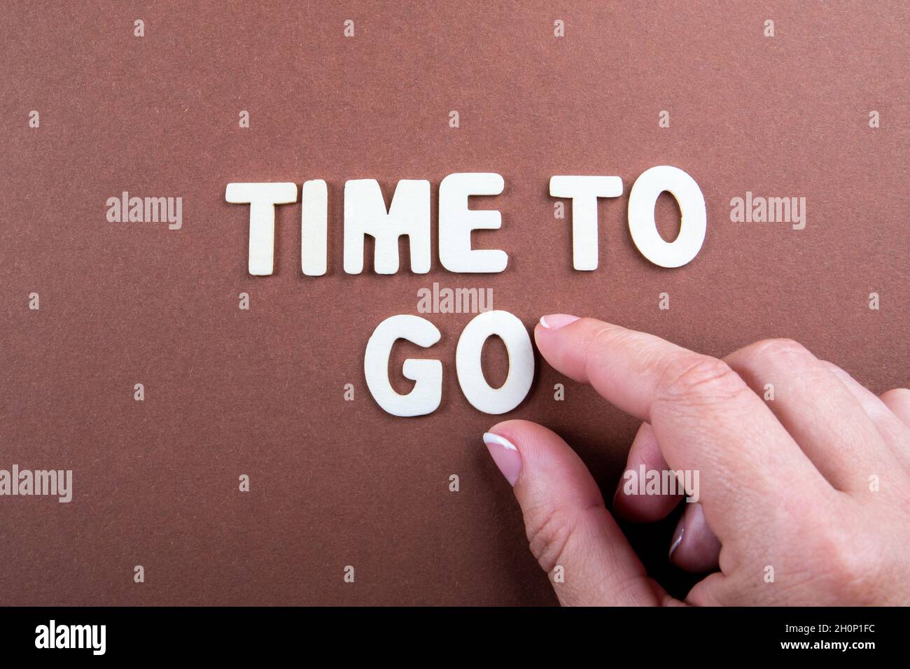 Time To Go. White letters of the alphabet and a woman's hand on a brown ...
