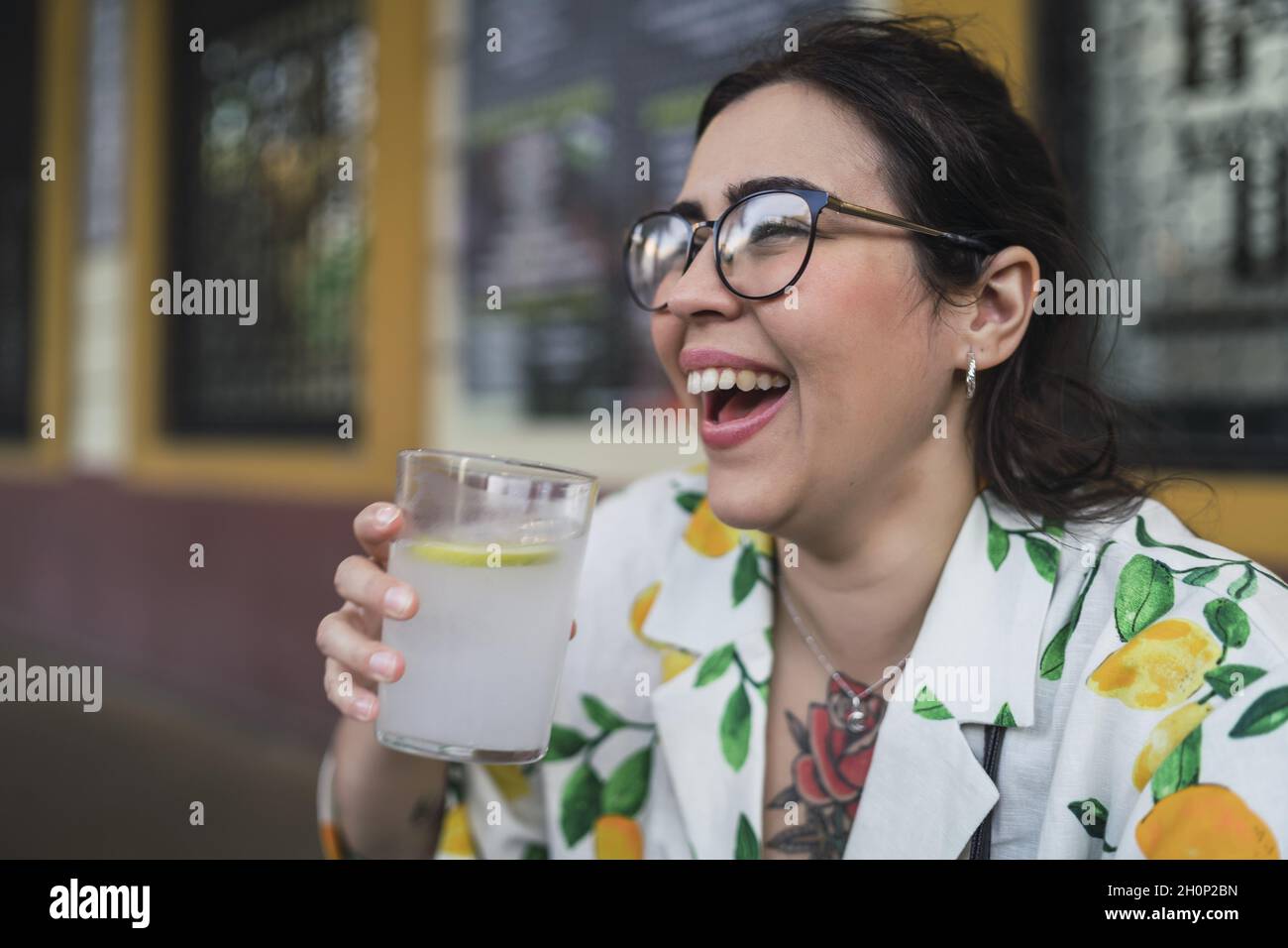 Shallow focus of a laughing Spanish girl having a drink outdoors Stock ...