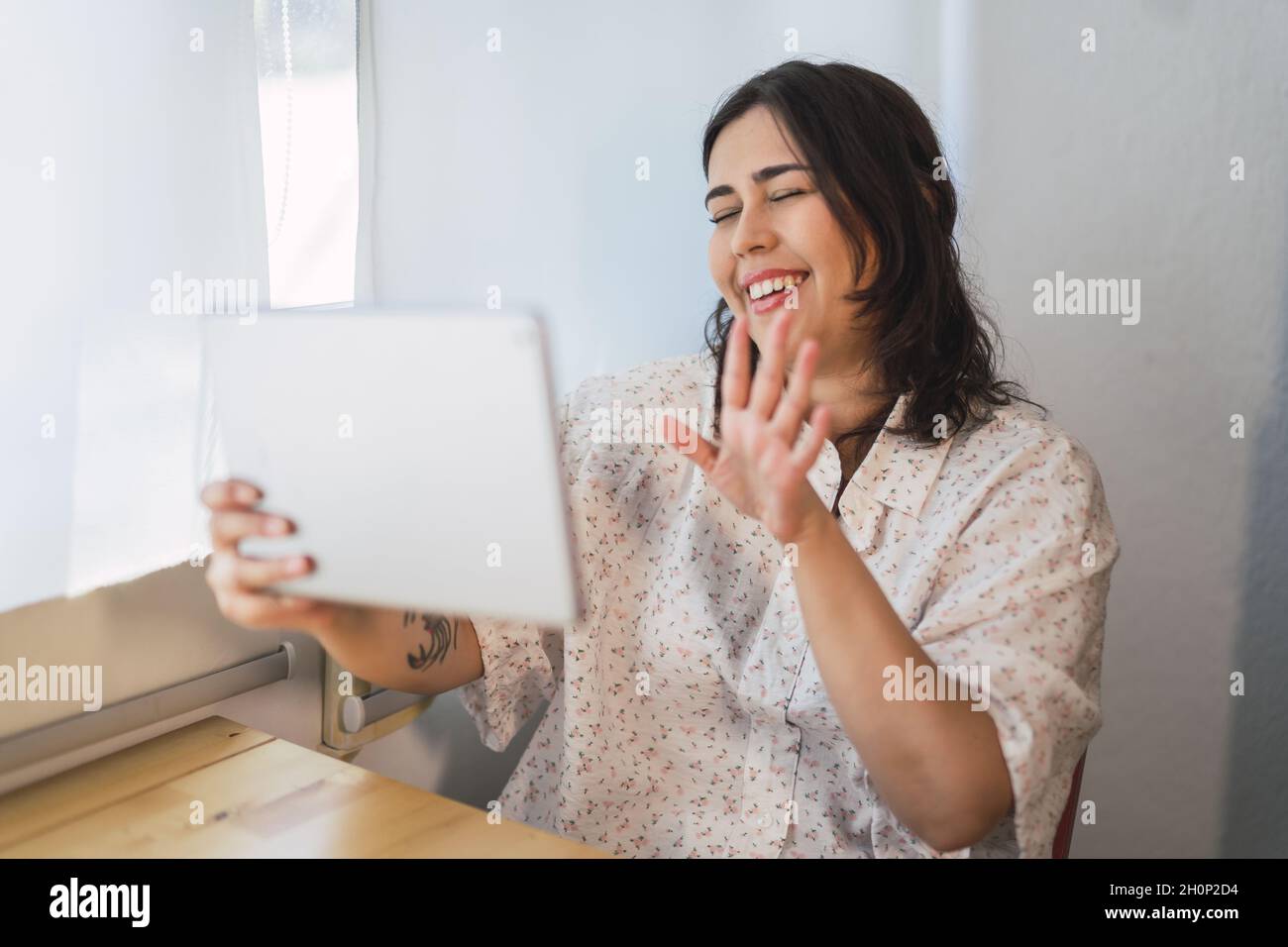 Shallow focus of a laughing Spanish girl using a tablet indoors Stock ...