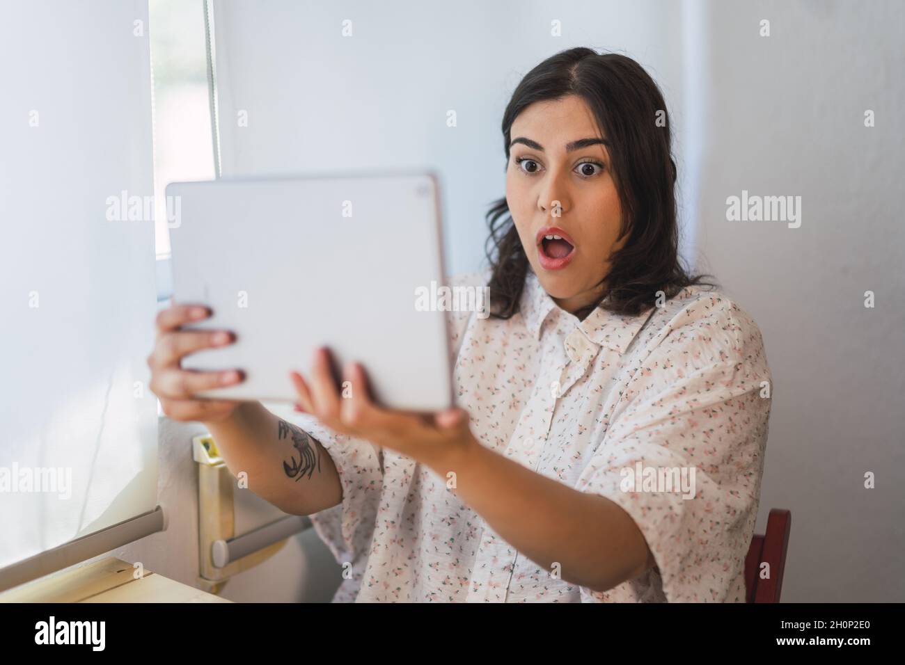 Shallow focus of a surprised Spanish girl using a tablet indoors Stock ...