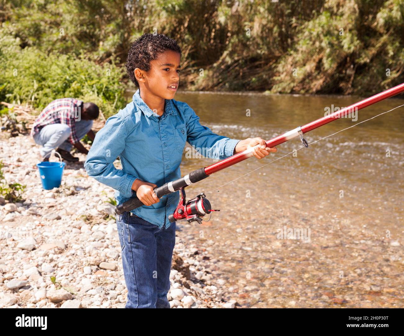 Boy pulling fish from river Stock Photo - Alamy