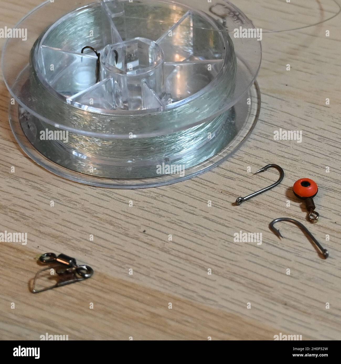 a reel with a fishing line and fish hooks are on the table Stock Photo ...