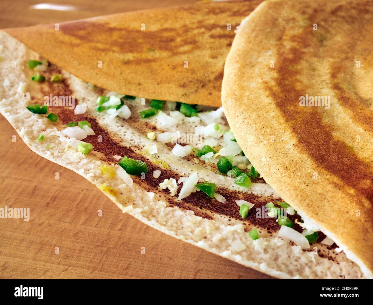 A dosa, the classic South Indian crepe, served with chili peppers and ...