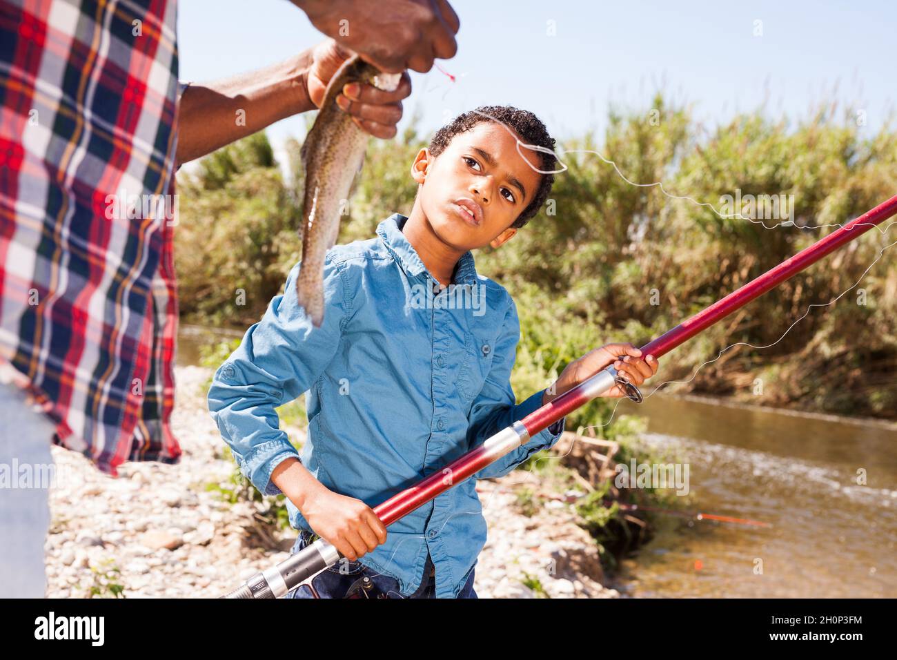 Boy and his father holding fishing rod Stock Photo - Alamy