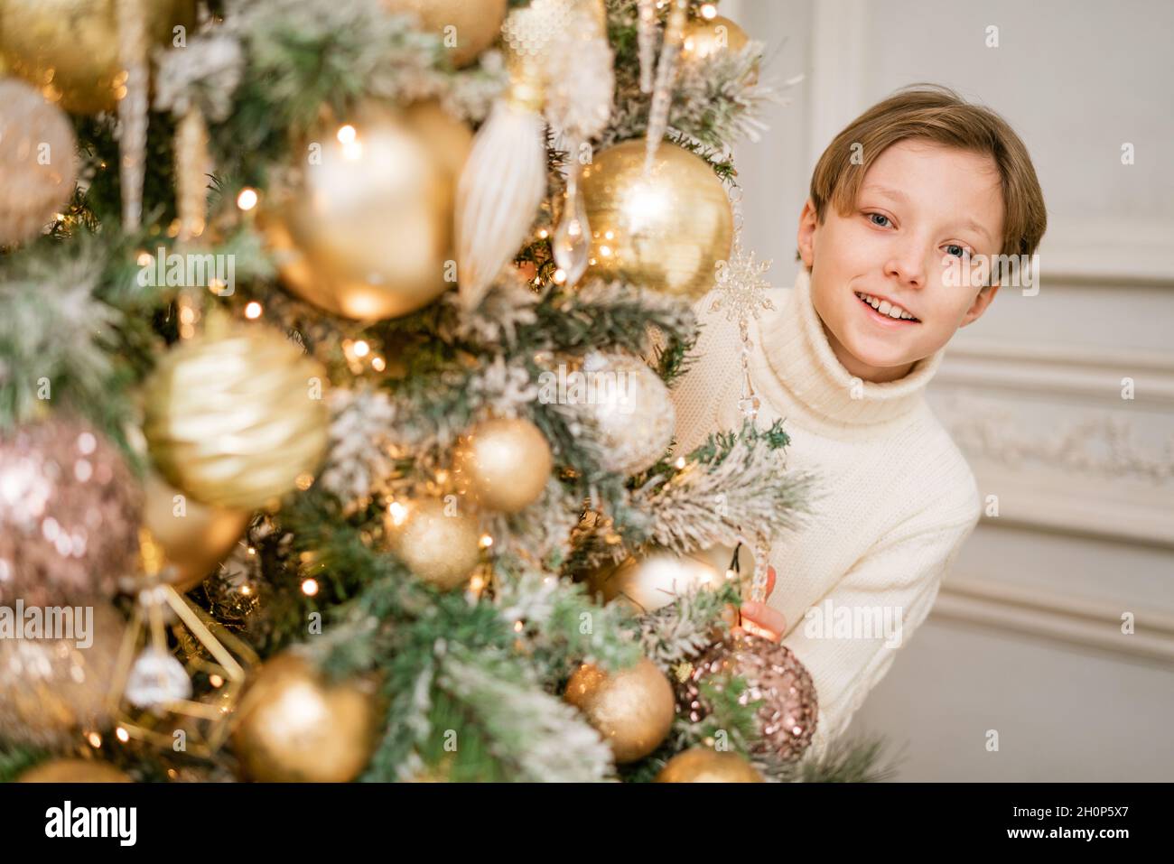 Happy guy in sweater at christmas tree decorates and looks out from ...